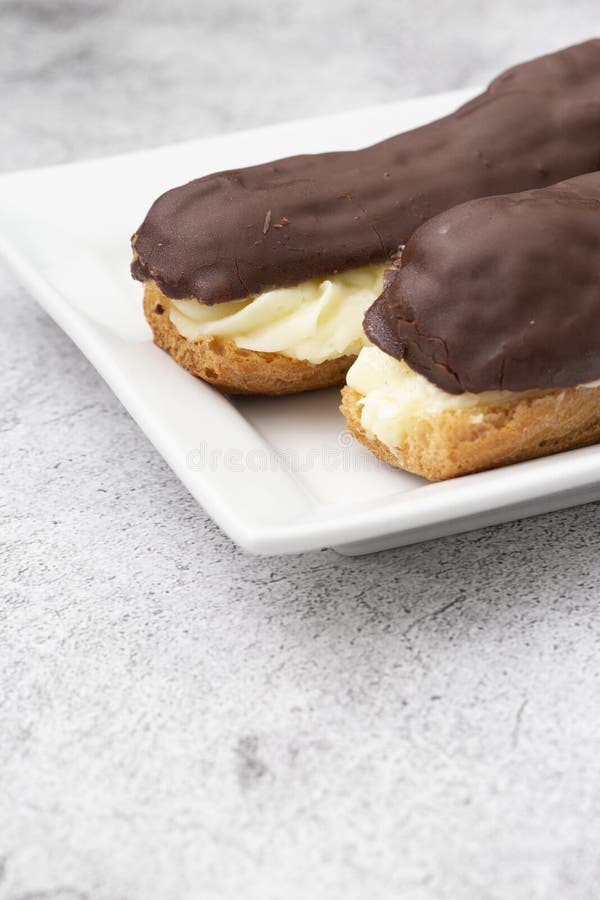 Chocolate Eclair with a Custard Cream Filling on a White Plate. Stock ...