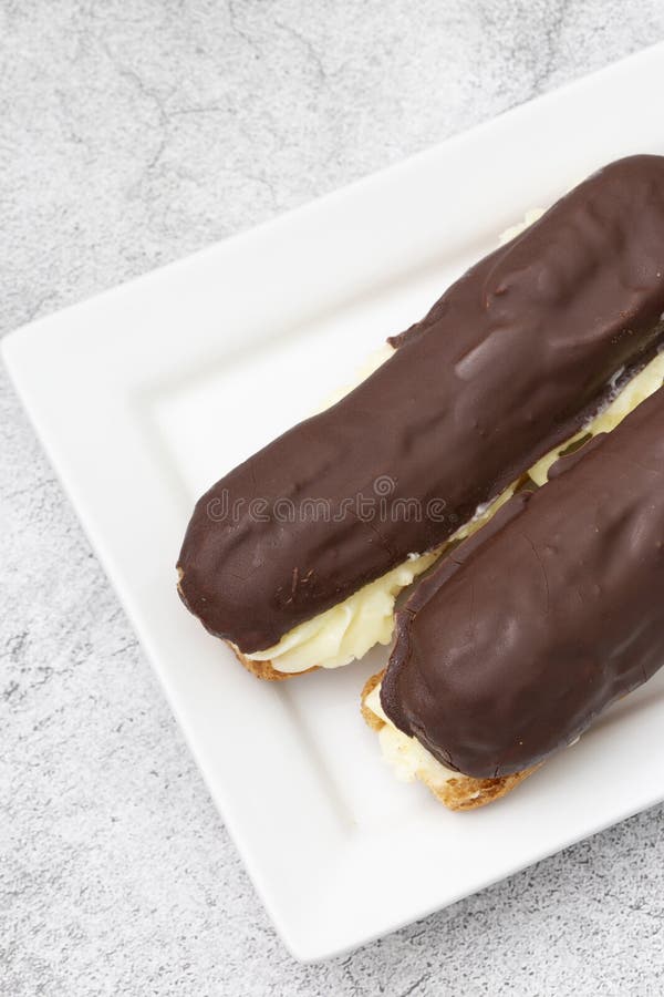 Chocolate Eclair with a Custard Cream Filling on a White Plate. Stock ...