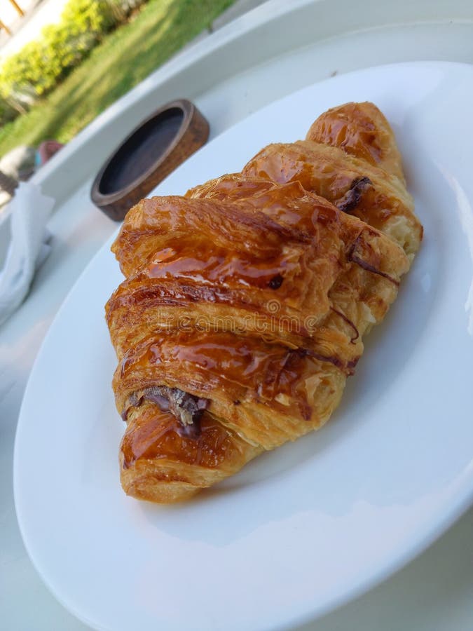 A Chocolate-flavored Croissant Served on a White Plate in a Cafe Stock ...