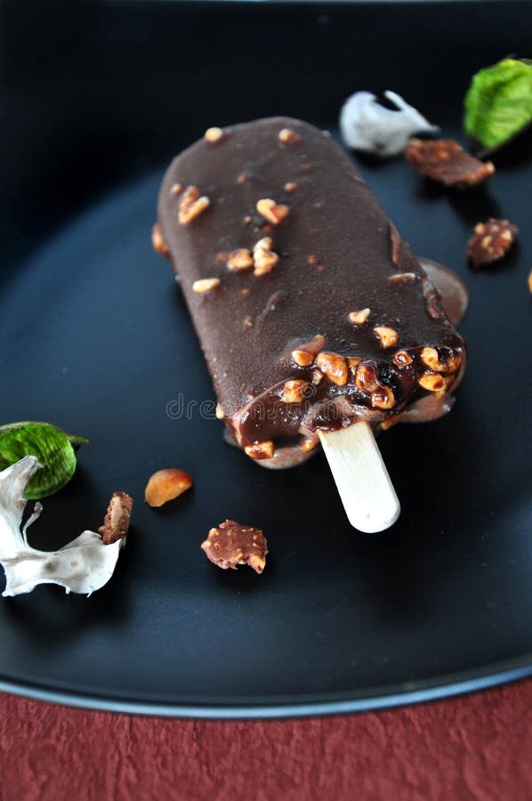 Chocolate Ice Cream Bar with Nuts Melting on Black Plate Stock Image ...