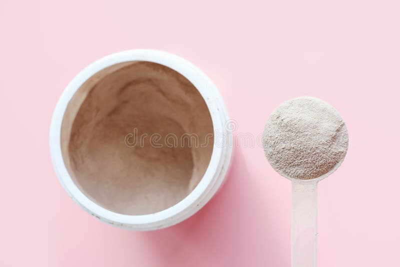 Chocolate Protein Powder in Scoop Against a Plastic Jar on Pink ...