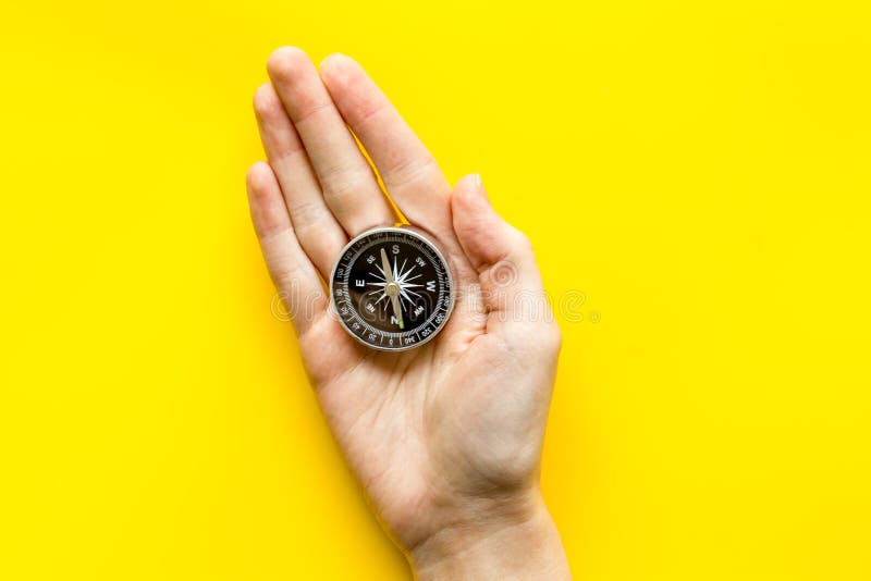 Choose Direction Concept. Compass in Hand on Yellow Background Top View ...