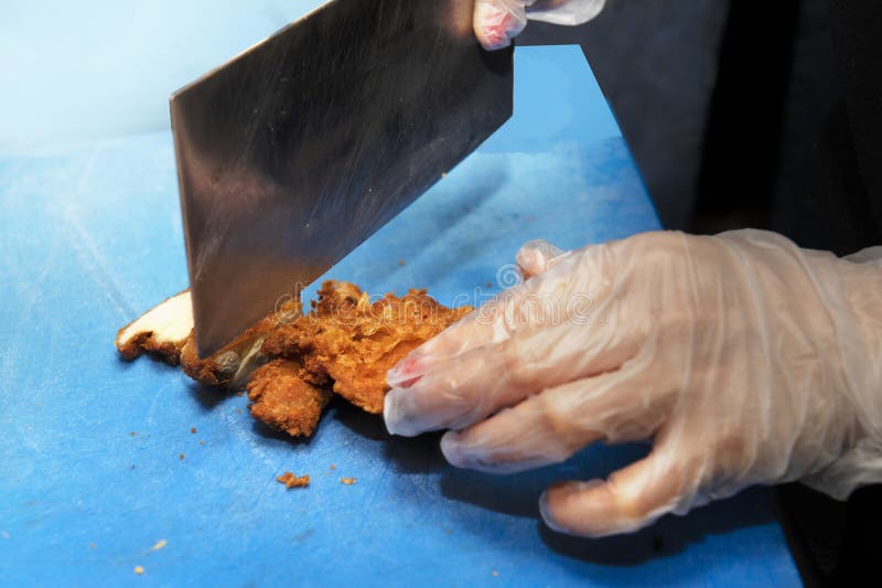 Chopping Chicken in Batter on a Blue Board with a Kitchen Machete in ...