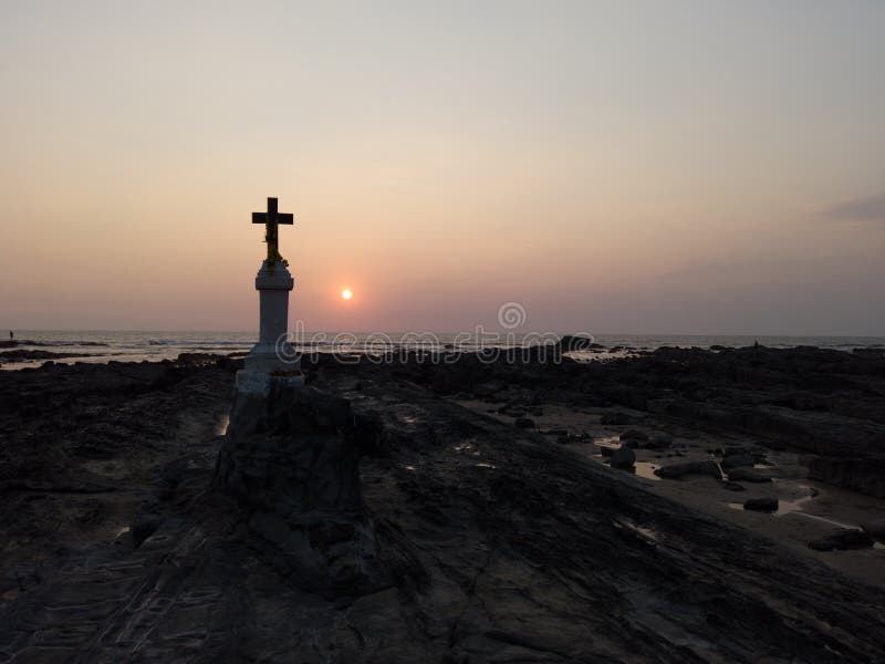 The Christian Cross on the Rocks by the Sea Against the Sunset. Stock ...