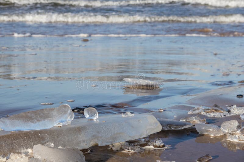 .chunks of Ice on a Sandy Beach with Water and Waves in the Background ...