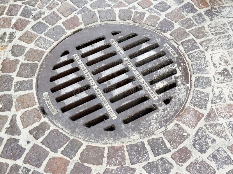 Circular Metal Storm Drain on Cobblestone Pavement with Weathered ...