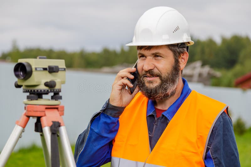 A Civil Engineer with an Optical Level Talking on a Mobile Phone. Stock ...