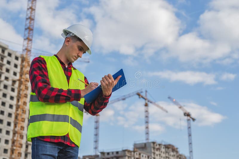 Civil Engineer in a White Helmet Makes Pencil Marks in the ...