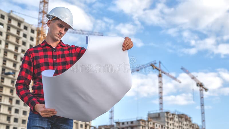 Civil Engineer in a White Helmet Looking Documents on the Background of ...