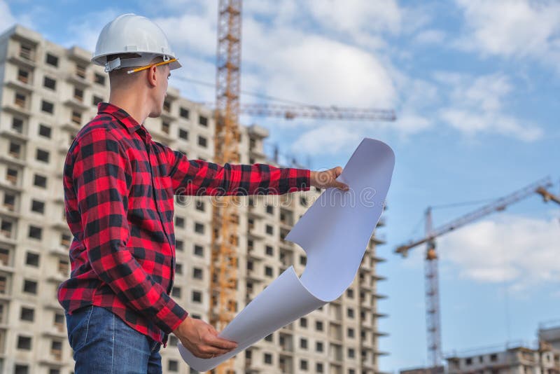 Civil Engineer in a White Helmet Looking Documents on the Background of ...