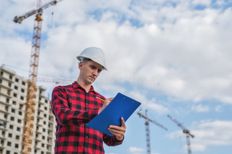Civil Engineer in a White Helmet Makes Pencil Marks in the ...