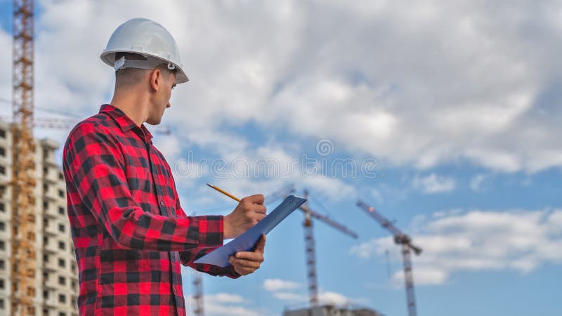 Civil Engineer in a White Helmet Makes Pencil Marks in the ...