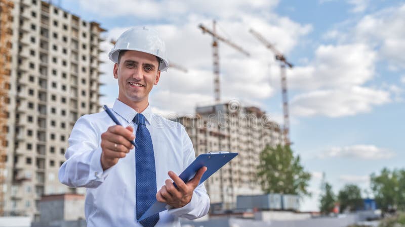 Civil Engineer in a White Helmet Makes Pencil Marks in the ...