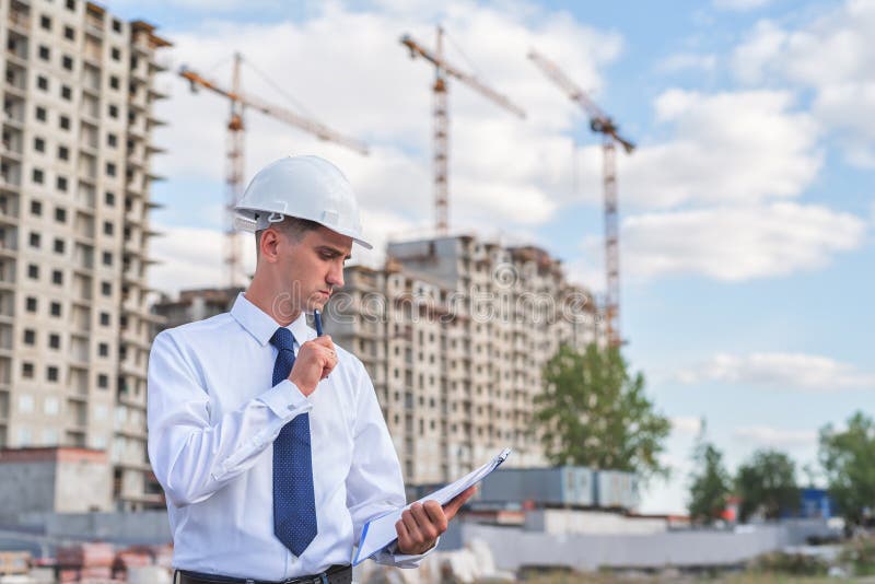 Civil Engineer in a White Helmet Makes Pencil Marks in the ...