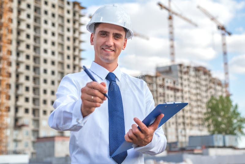 Civil Engineer in a White Helmet Makes Pencil Marks in the ...