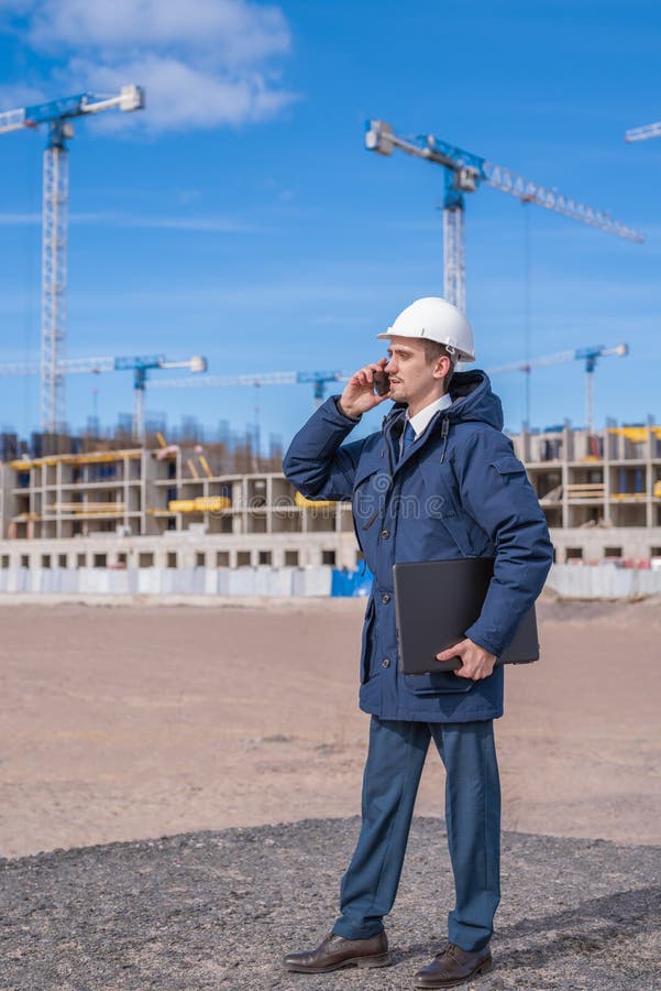 A Civil Engineer in a White Helmet is Talking on the Phone in the ...