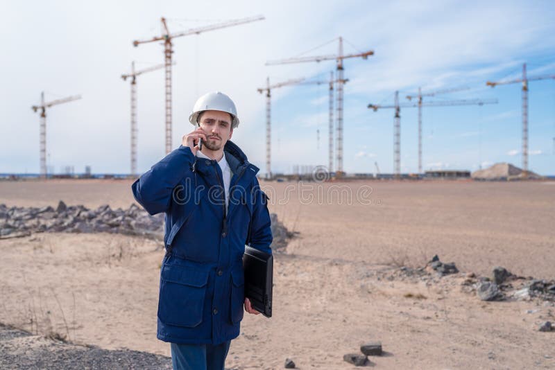 A Civil Engineer in a White Helmet is Talking on the Phone in the ...