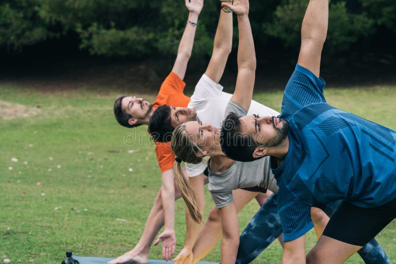 Class with Four People in Line Practising the Triangle Pose of Yoga ...