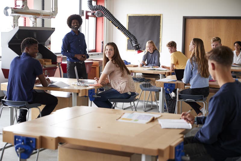 Class of High School Students Sitting at Work Benches Listening To ...
