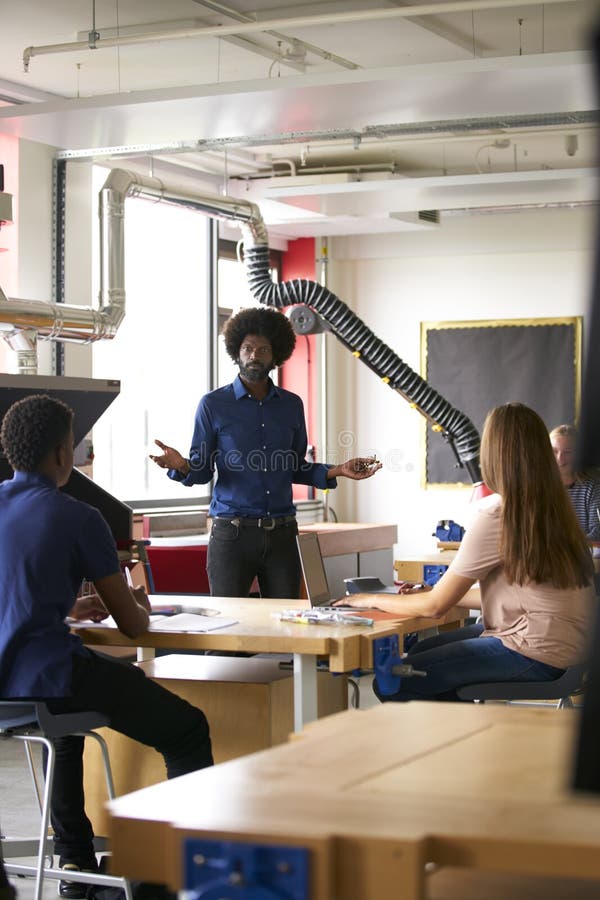 Class of High School Students Sitting at Work Benches Listening To ...