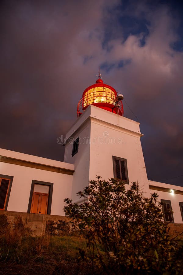 The Classic Illuminated Lighthouse with a Lamp on during the Sunset ...