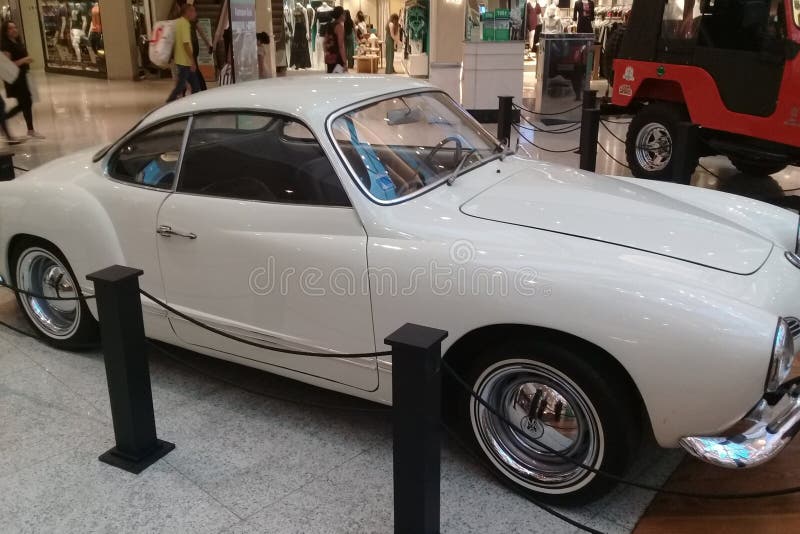 A Classic White Car Displayed Indoors Surrounded by Black Posts and ...