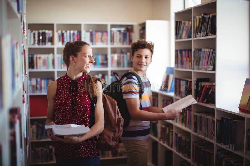 Classmates Interacting while Selecting Book in Library Stock Photo ...