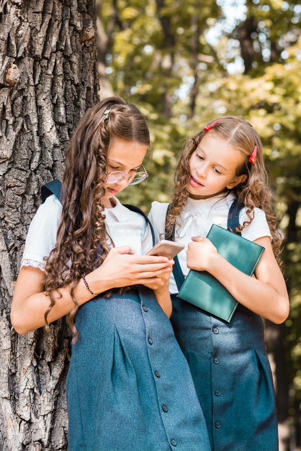 A Pupil in a School Uniform with a Book Walks in the Park on a Warm Day ...