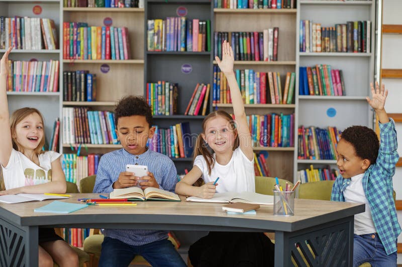 Mixed-race Pupils Study and Write at Table in Library or Classroom ...