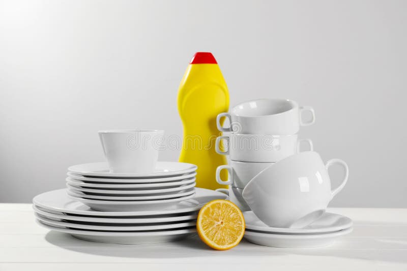 Clean Tableware, Dish Detergent and Half of Lemon on White Wooden Table ...