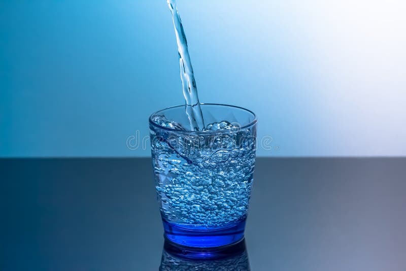 Clean Water is Poured into a Glass Standing on a Black Table. Blue ...
