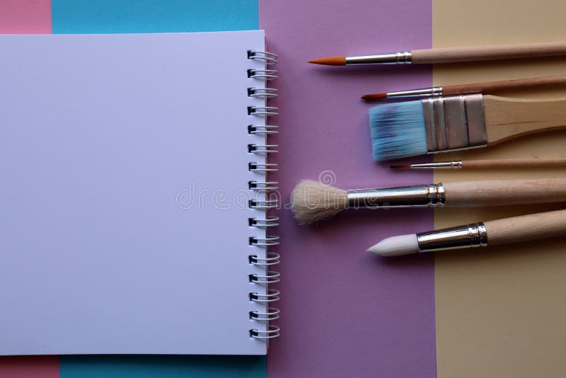 A Clean White Notebook and Brushes on Pink and Blue Background with ...