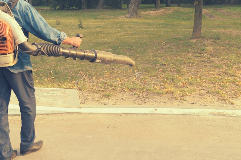 The Cleaner Blows the Fallen Leaves with a Special Pneumatic Gun. Stock ...