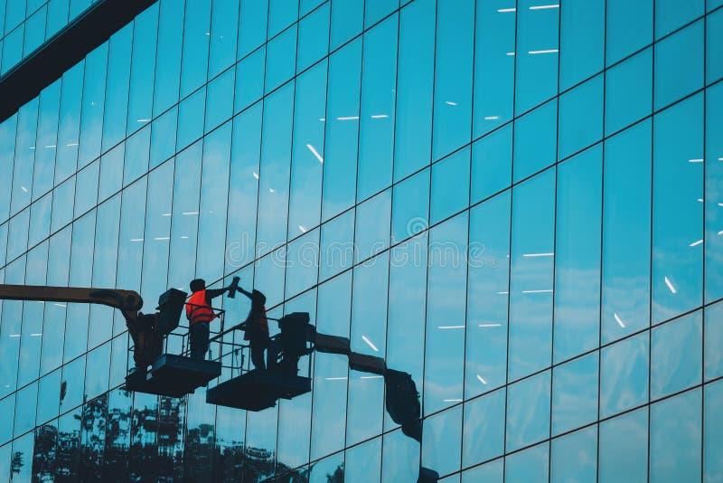 Cleaner Worker Using a Cherry Picker To Clean a Glass Facade of a ...