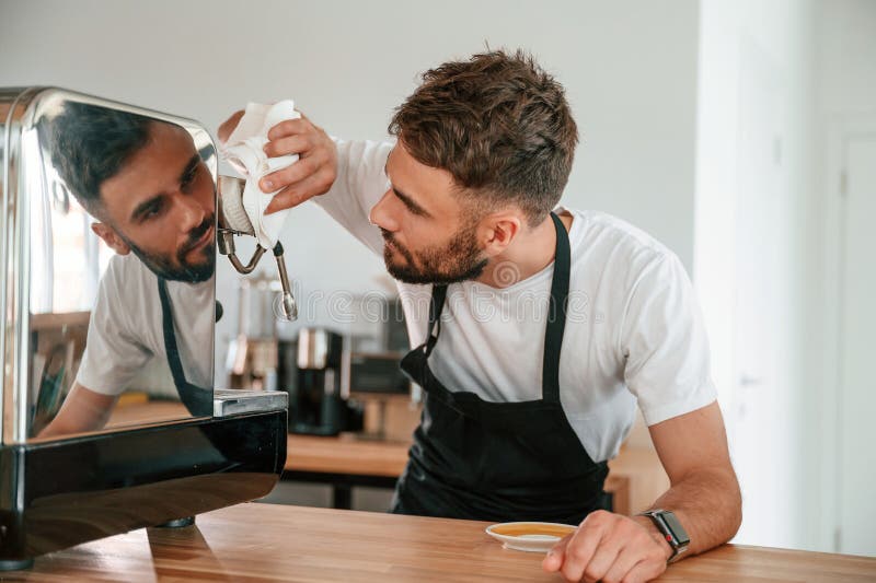 Cleaning Coffee Machine. Cafe Worker in White Shirt and Black Apron is ...