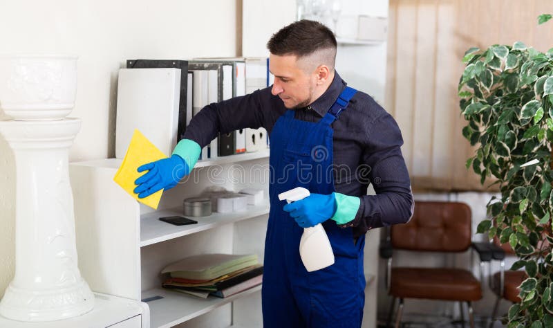 Cleaning Man in Overalls Wipes Dust from Table in Office Stock Photo ...