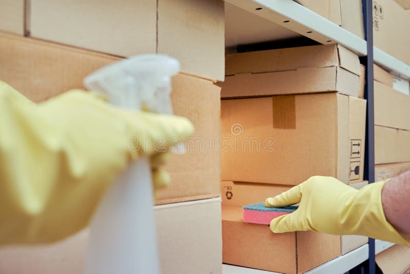 Cleaning in a Warehouse, a Man in Yellow Gloves Wipes Boxes with Goods ...