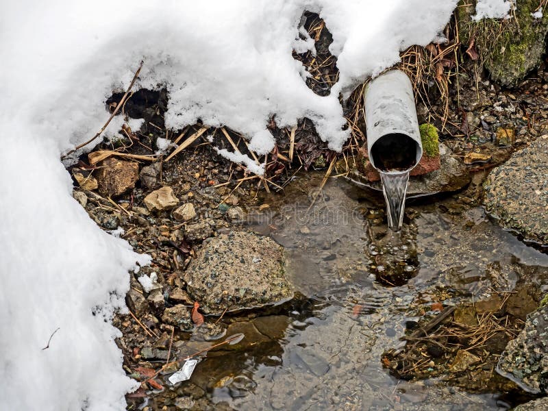 Clear, Clean Water from a Spring Source Flows from a Pipe into a Rocky ...