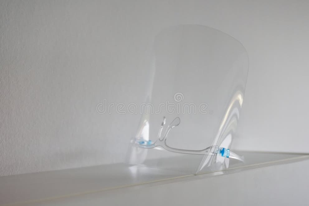 A Clear Face Shield Resting on a White Surface, Featuring Blue ...