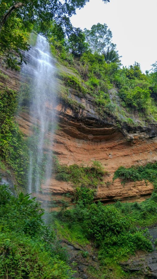 A Clear Waterfall with Water Falling Rapidly between Tall Red Rocks in ...