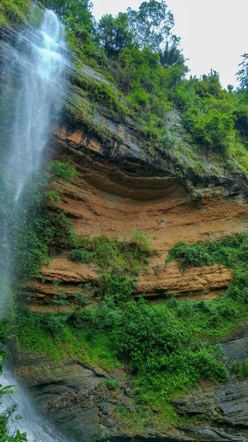 A Clear Waterfall with Water Falling Rapidly between Tall Red Rocks in ...
