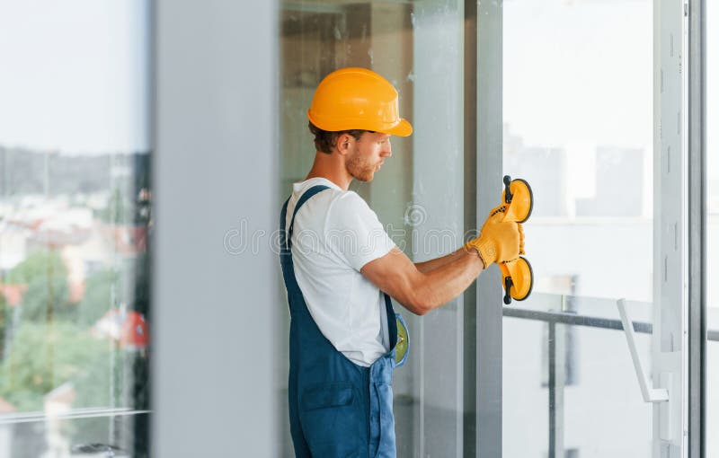 Clearing Windows. Young Man Working in Uniform at Construction at ... Clearing Windows. Young Man Working in Uniform at Construction at ...