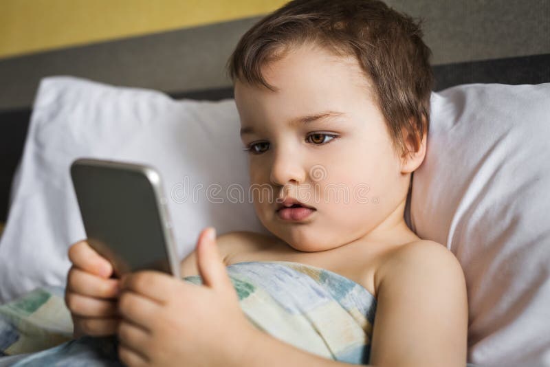 Clever Cute Boy Playing with Phone Lying on the Bed in Morning Stock ...
