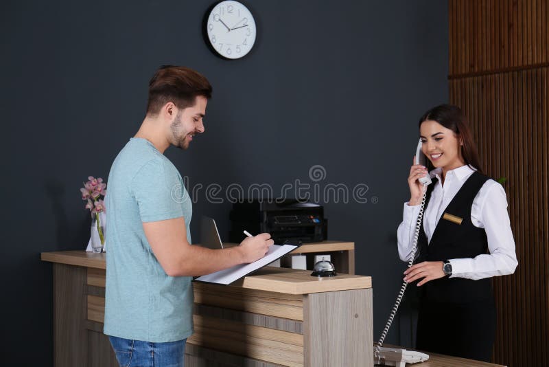Client Registering at Desk while Receptionist Talking on Phone Stock ...