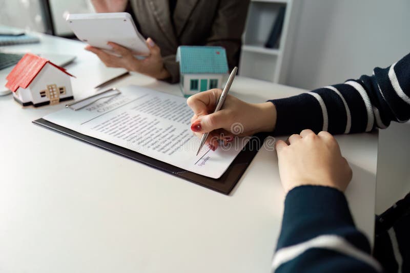 Man Signing Real Estate Contract Papers with Small Model Home in Front ...
