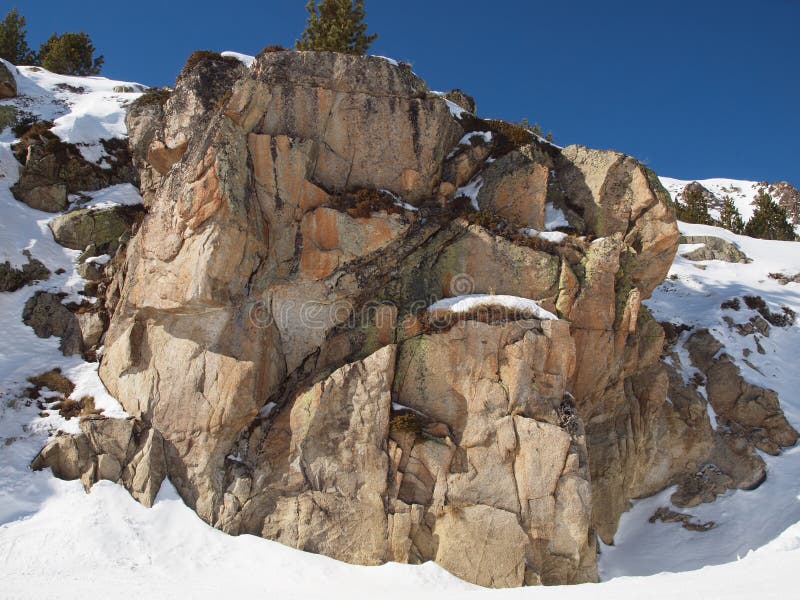 A Cliff on a Snowy Slope Against the Blue Sky with a Lone Tree on Top ...