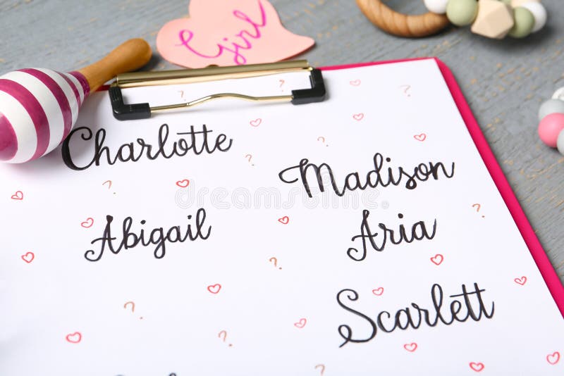 Clipboard with Different Baby Names and Toys on Grey Table Closeup ...