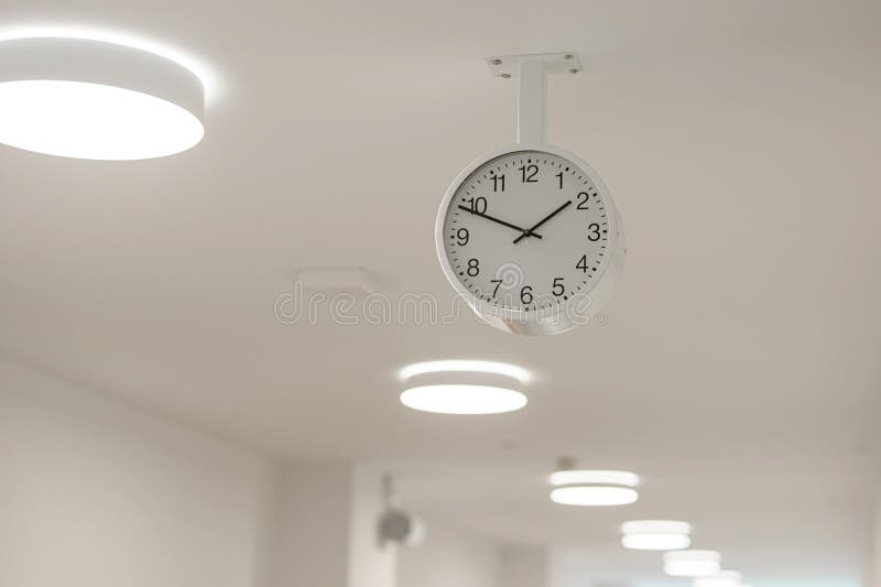A Clock Above the Ceiling in the Hallway of an Office Building Stock ...