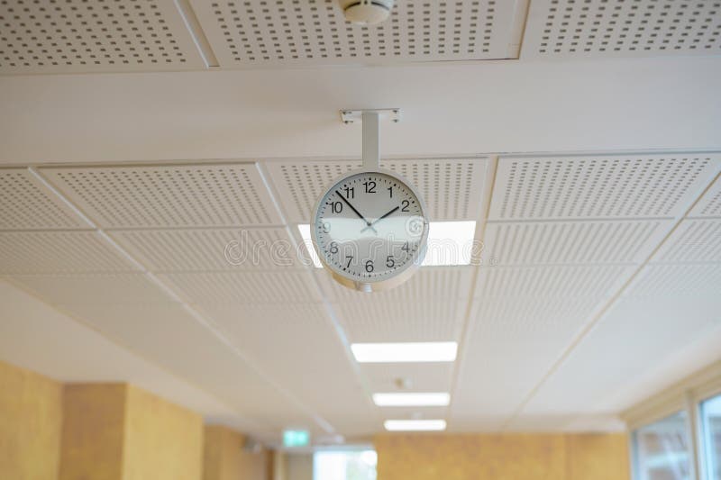 A Clock Above the Ceiling in the Hallway of an Office Building Stock ...