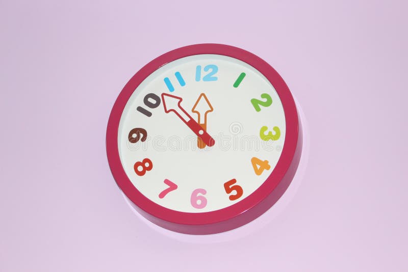 A Clock with Multi-colored Numbers on the Dial Hangs on a Pink Wall ...